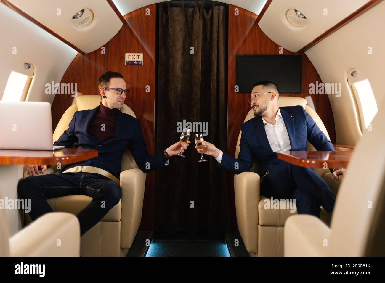 Two Elegant businessman couple in first class private airplane jet ...