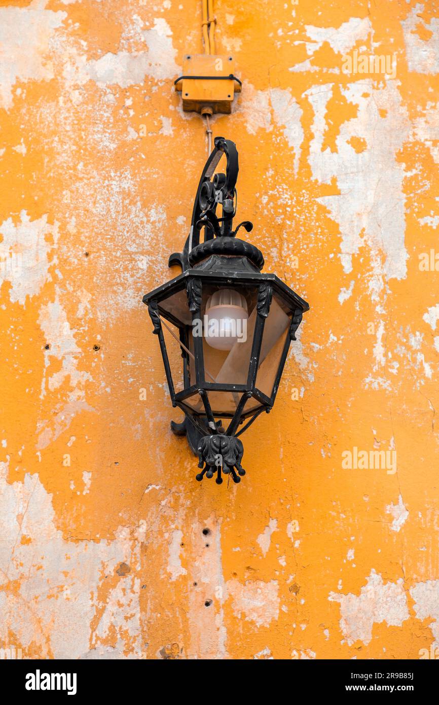 Old metal lantern, street light mounted on a shabby yellow wall in ...