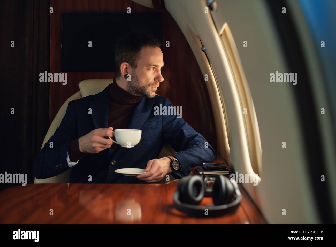 Elegant CEO young businessman in a jacket sitting inside in first class ...