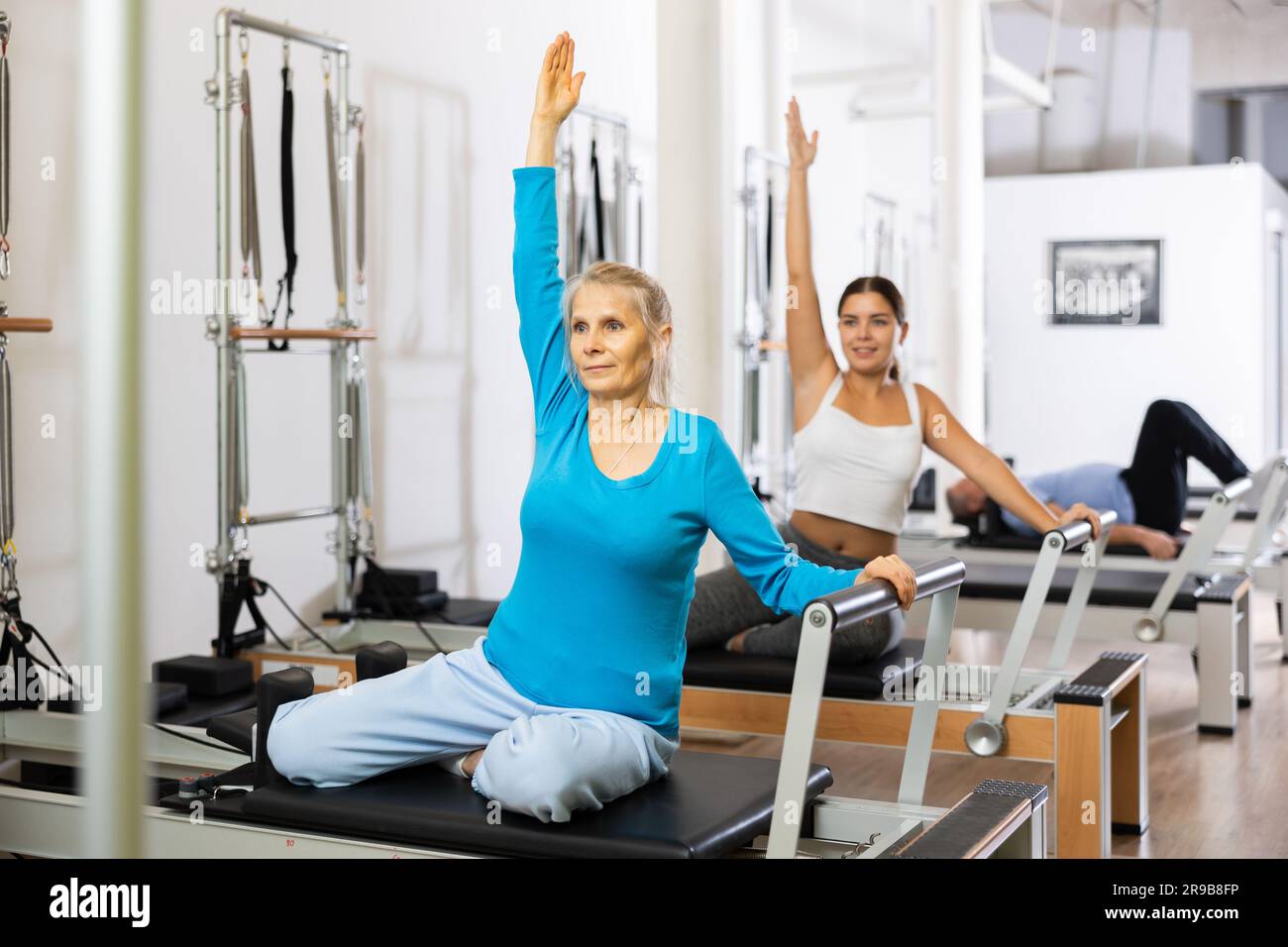 Mature woman in sportswear sitting and doing Pilates exercises for ...