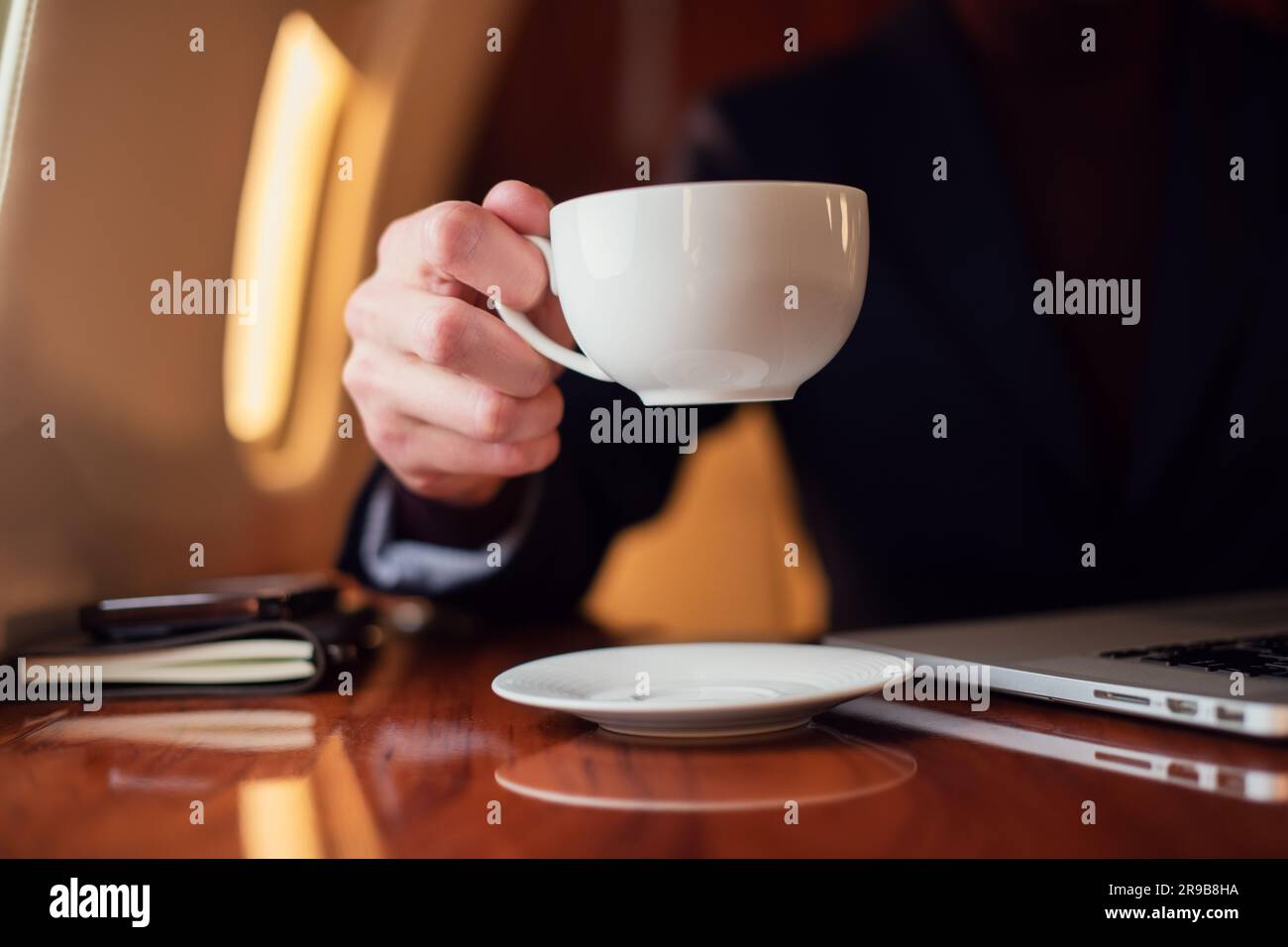 Close-up of businessman reaching for a cup of coffee in private ...
