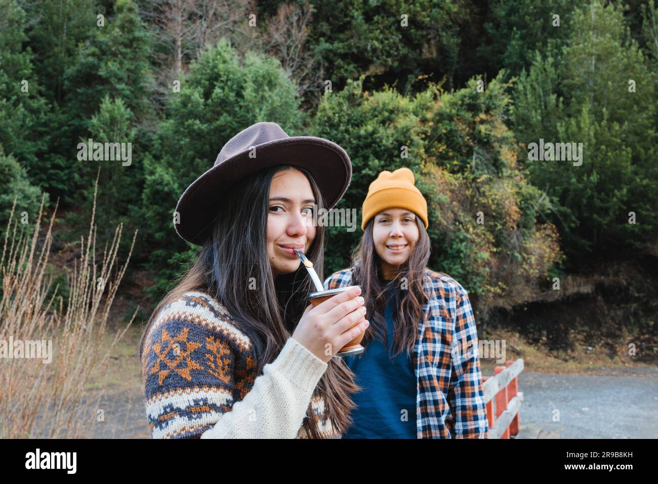Two Smiling Women Enjoying Yerba Mate in Countryside, Wearing Warm ...