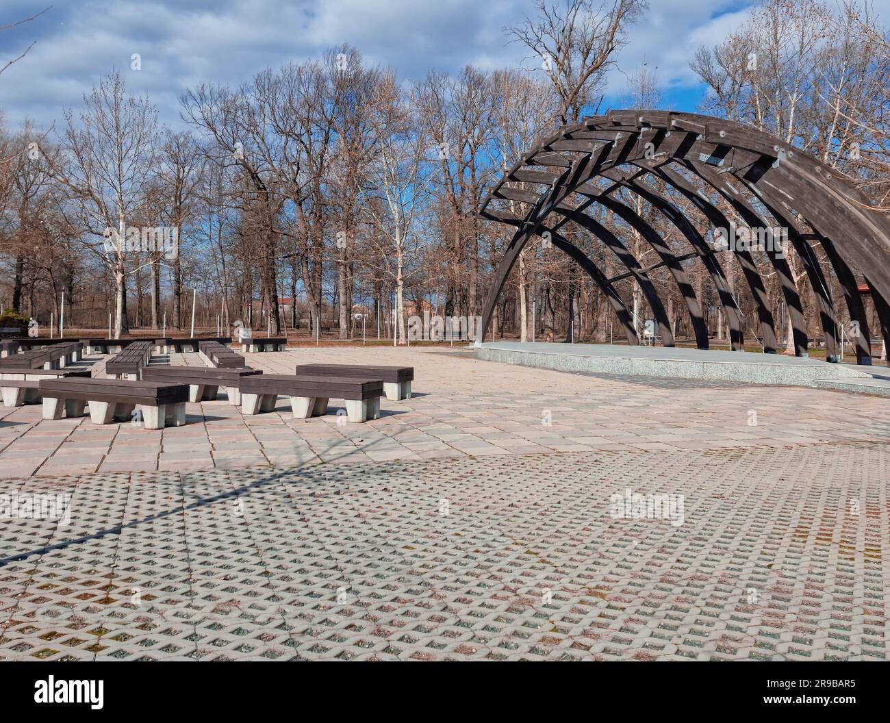 A wooden bench is situated in front of a large open-air structure ...