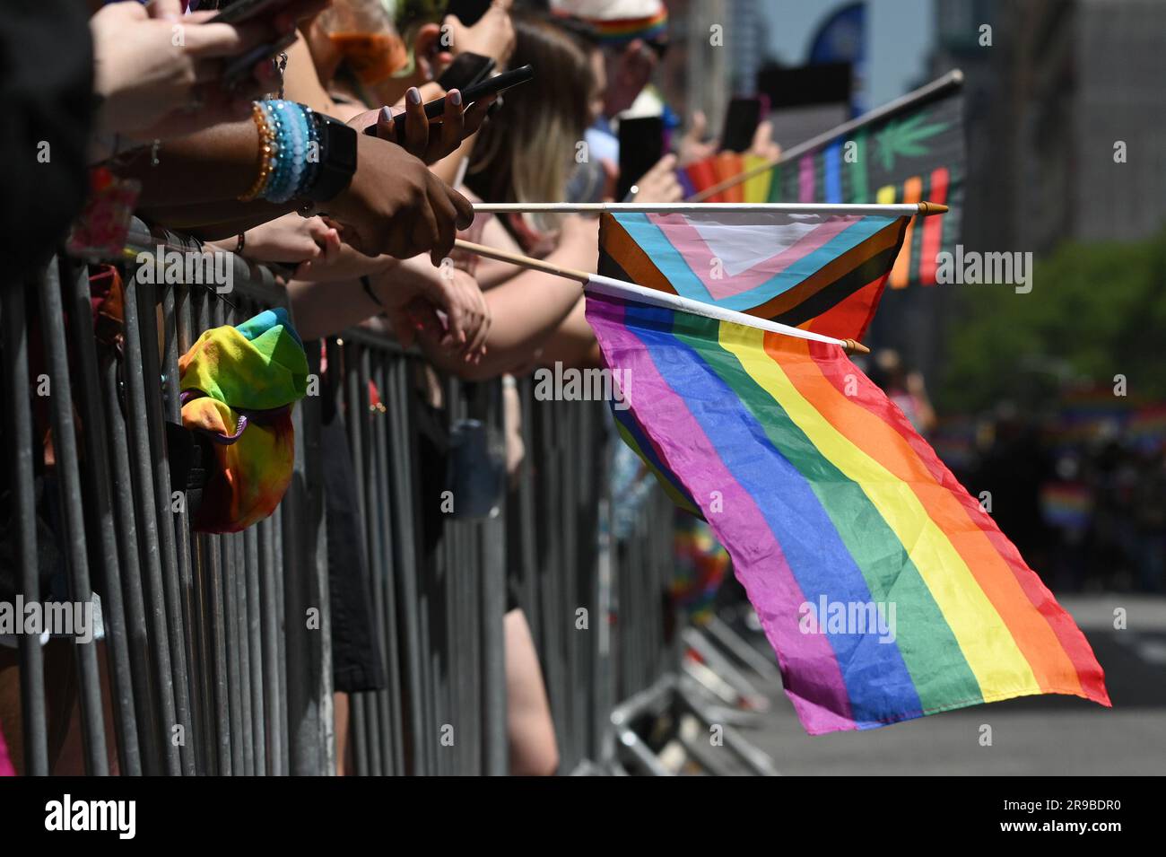 New York, USA. 25th June, 2023. Parade-goers hold pride-themed flags as ...