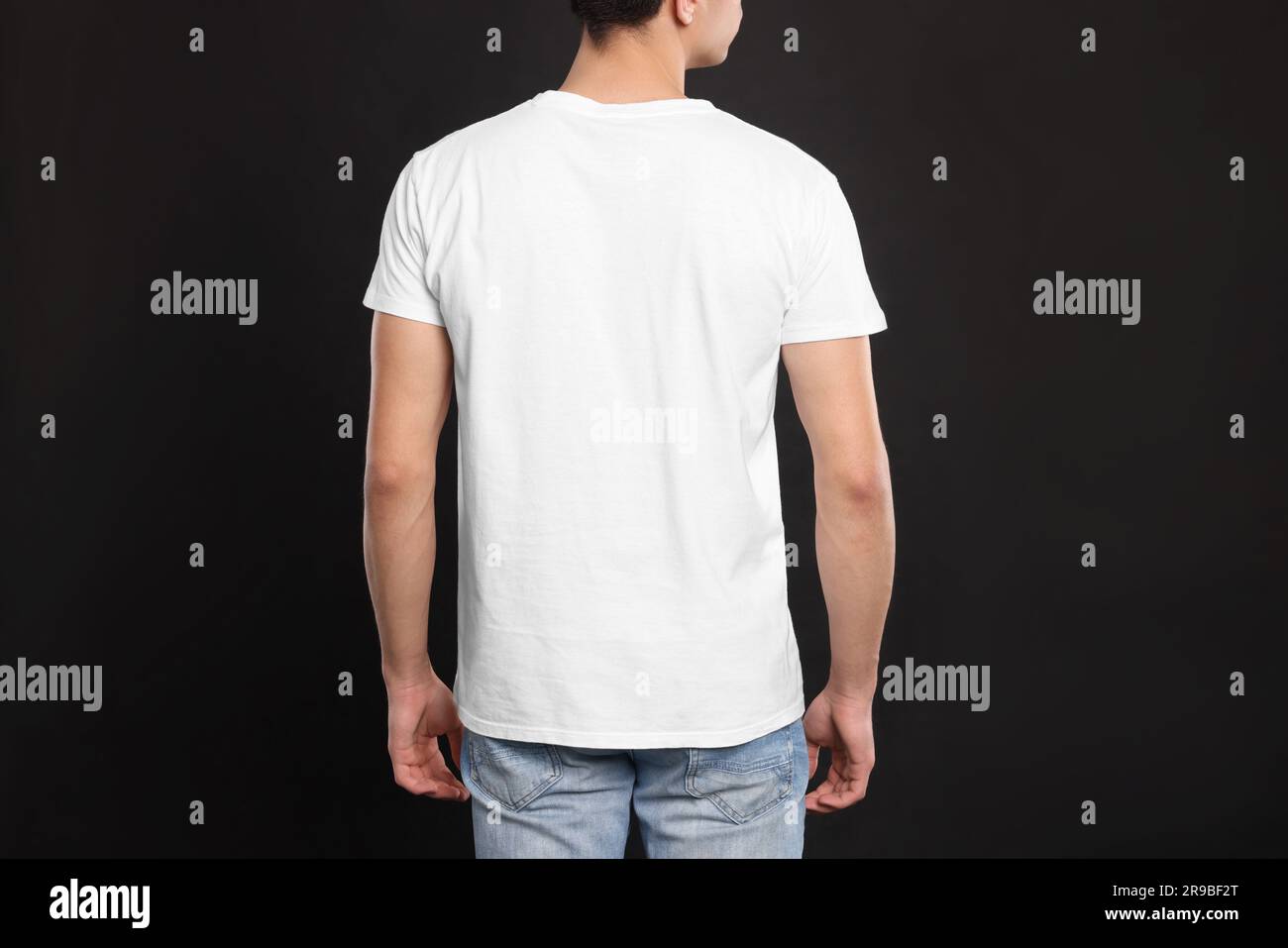 Man wearing white t-shirt on black background, back view. Mockup for ...