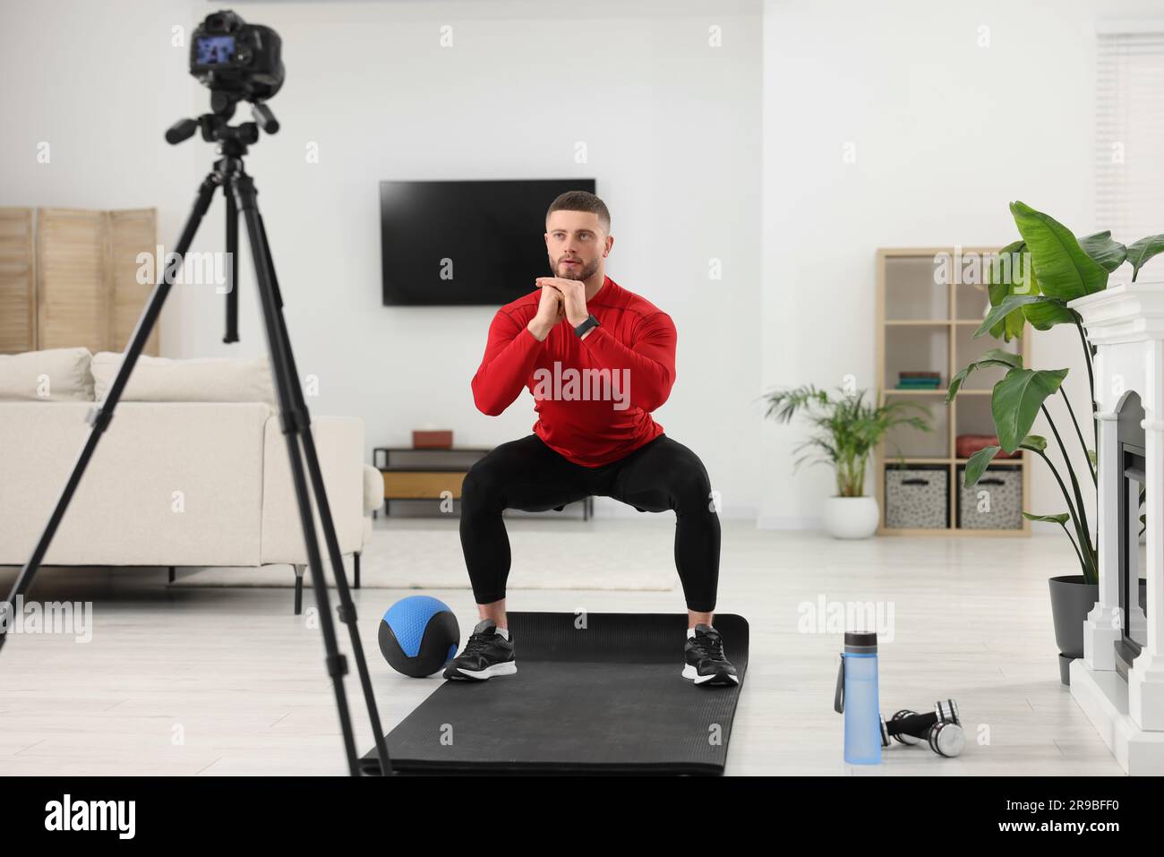 Trainer recording workout on camera at home Stock Photo - Alamy