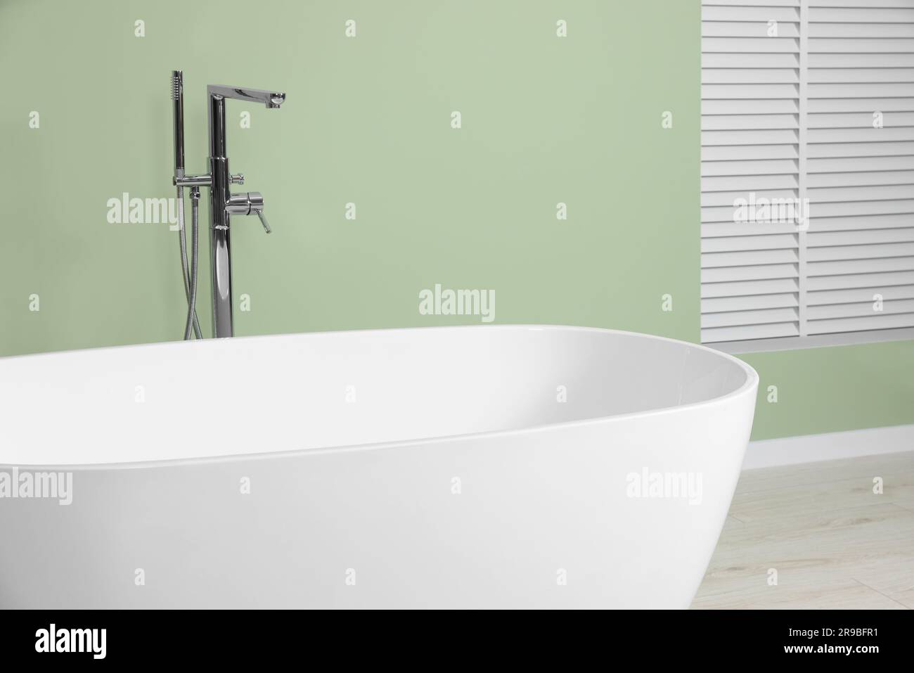 Modern ceramic tub near light green wall in bathroom, closeup. Interior ...