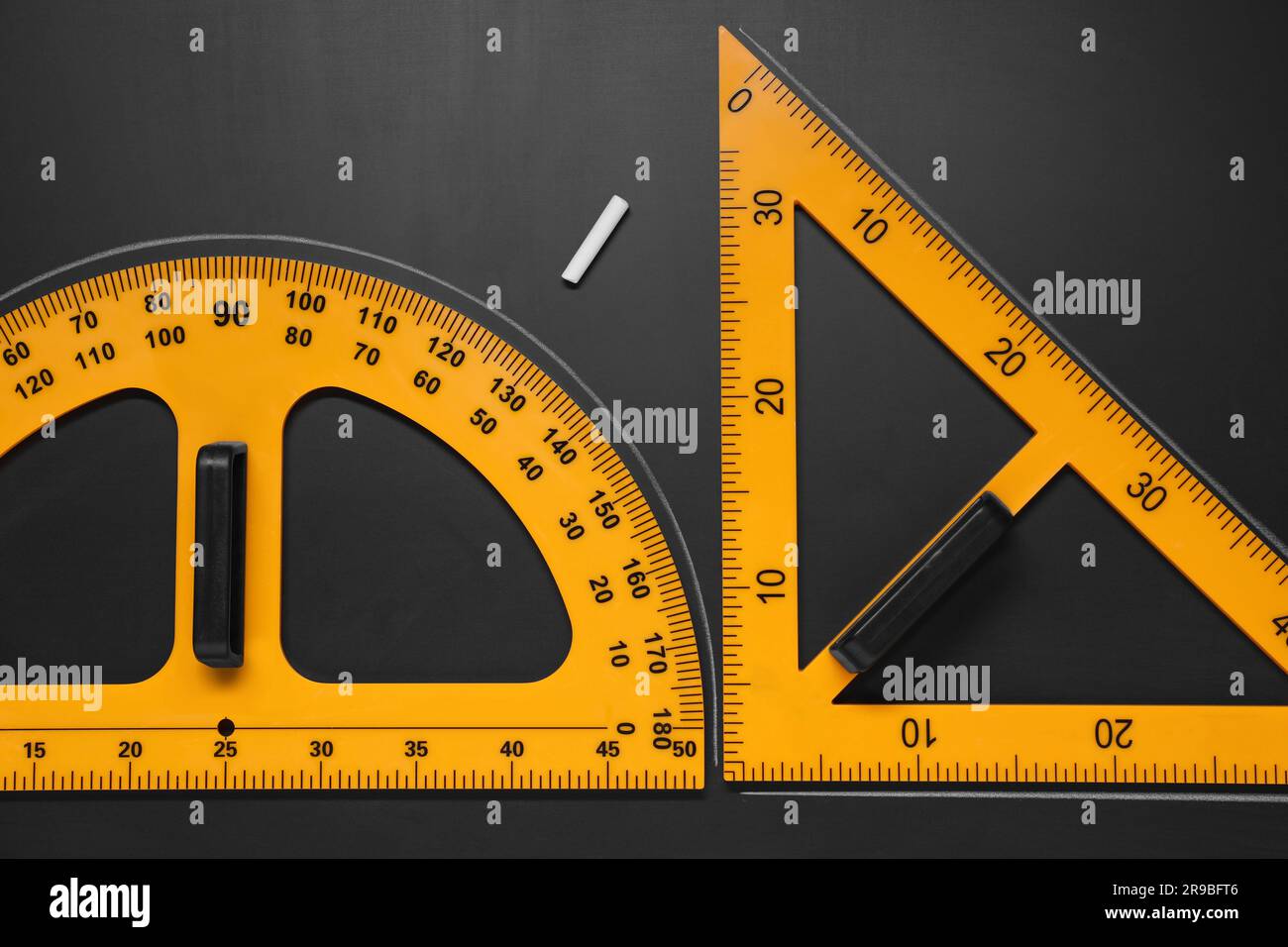 Protractor, triangle ruler and chalk on black table, flat lay Stock ...