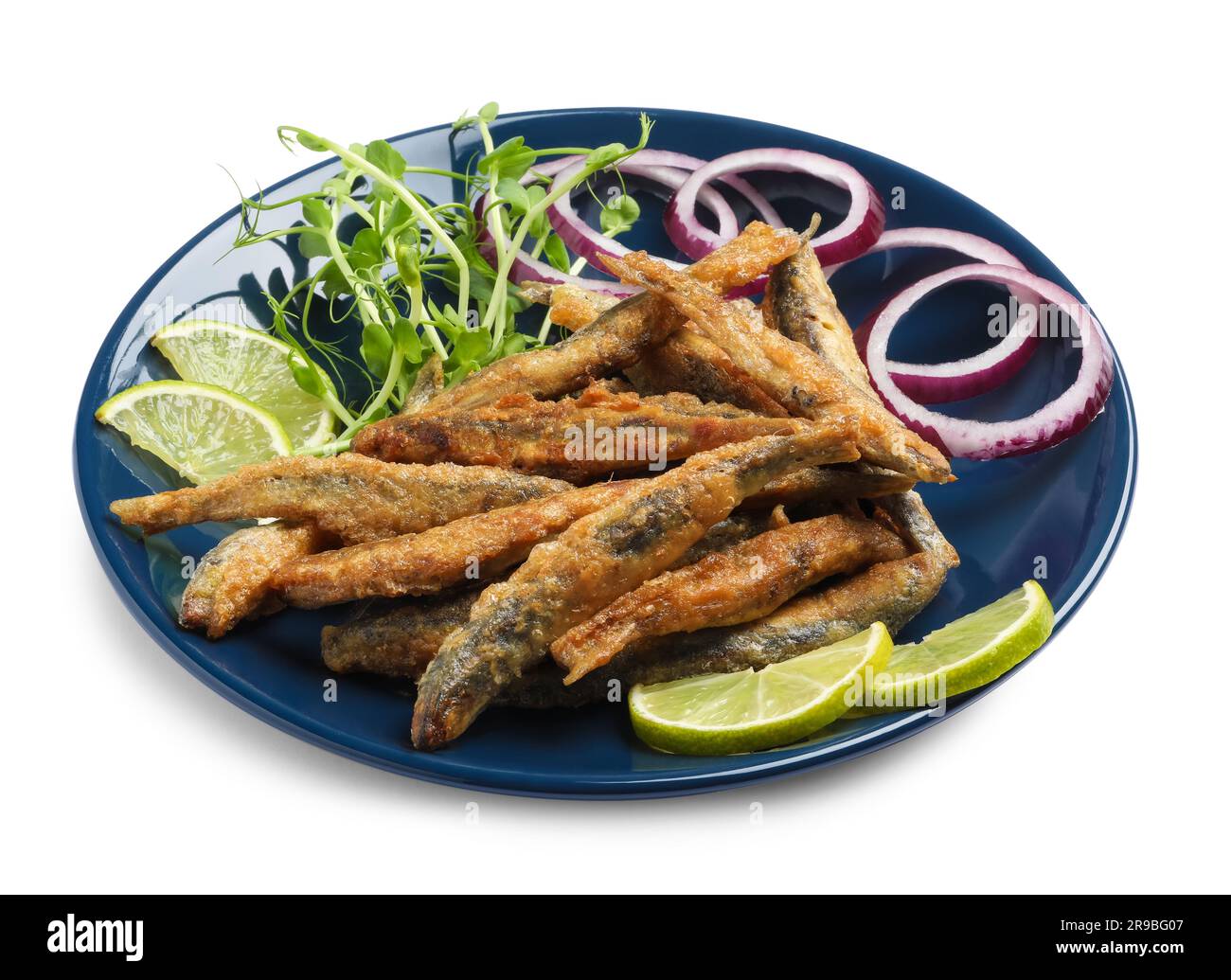 Plate with delicious fried anchovies, lime slices, microgreens and ...