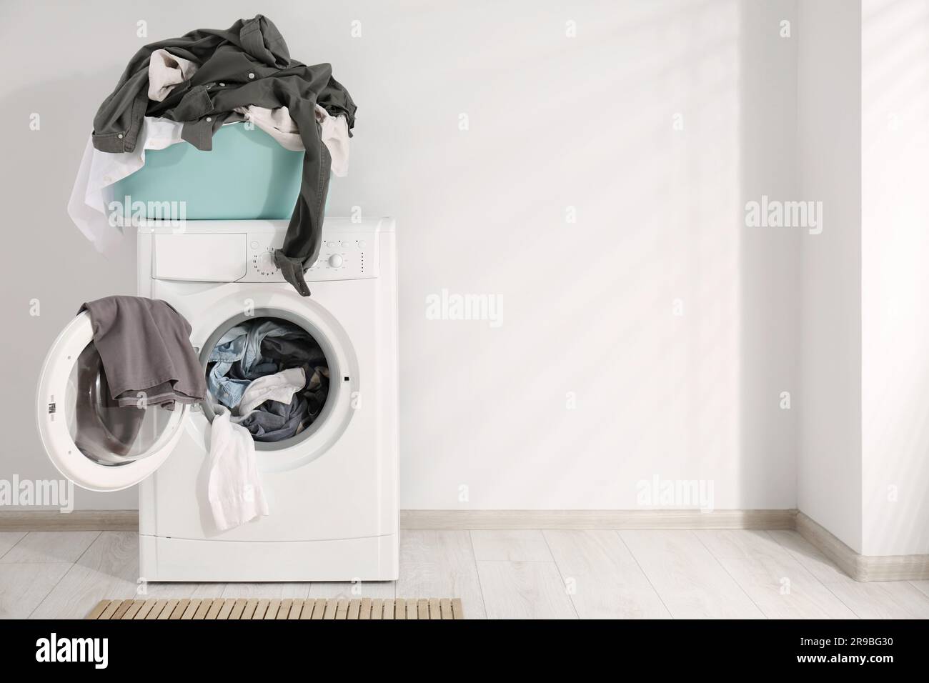 Laundry basket with clothes on washing machine indoors, space for text ...