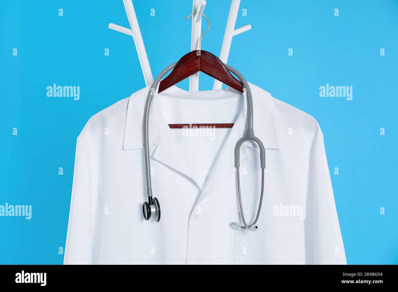 White medical uniform and stethoscope hanging on rack against light ...