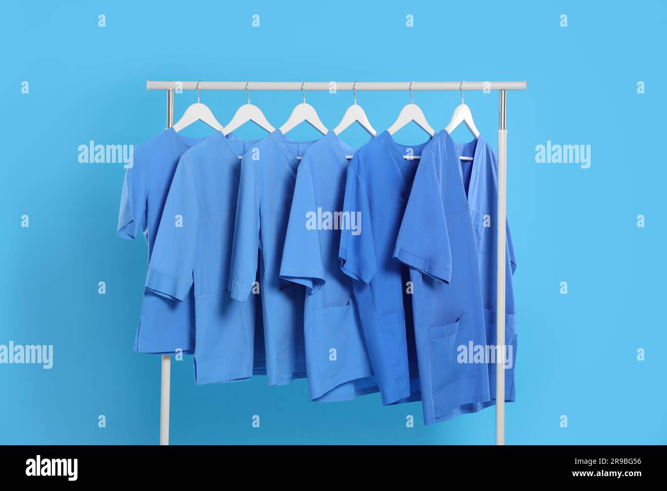 Medical uniforms on rack against light blue background Stock Photo - Alamy