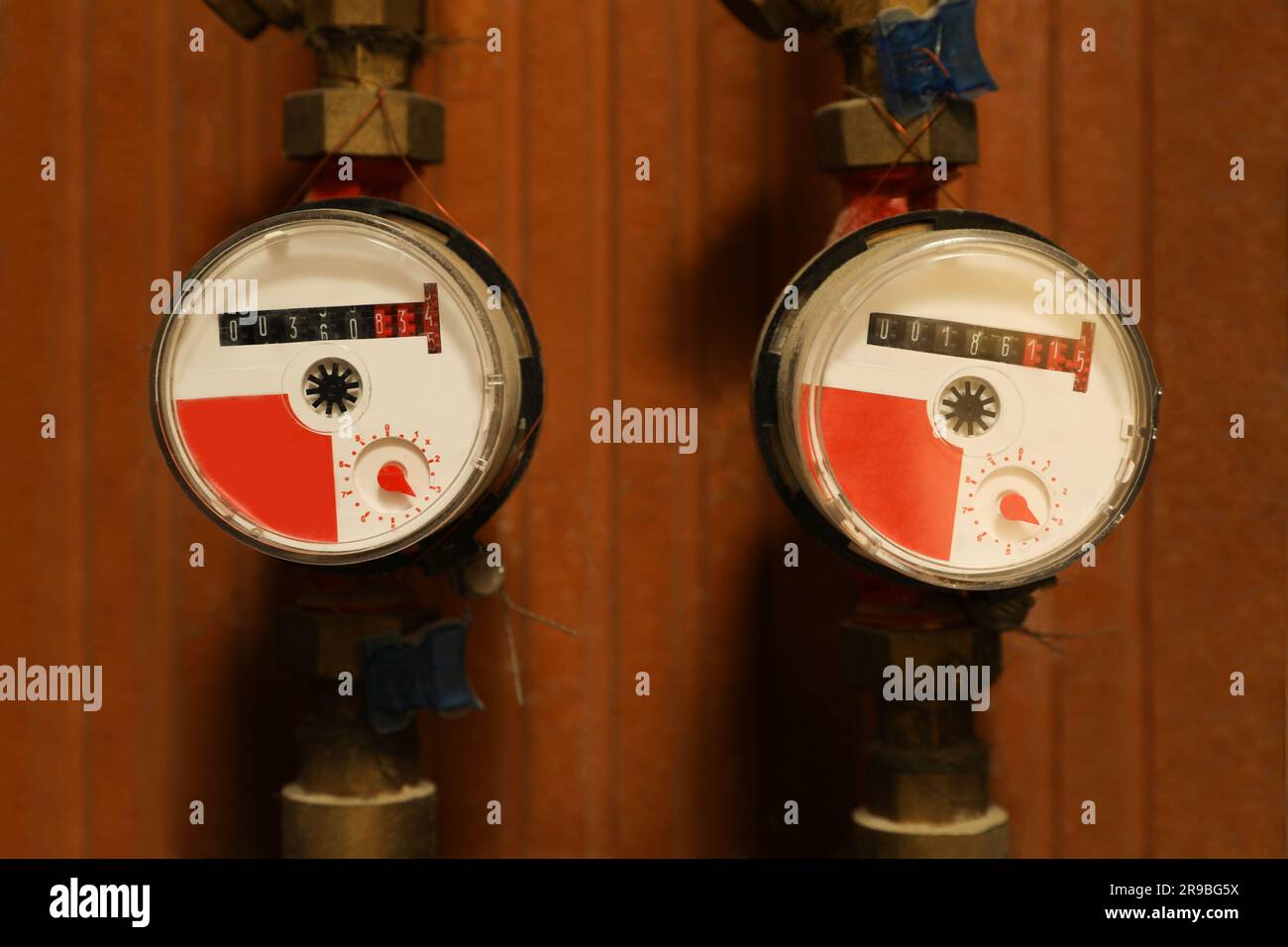 View of two electric meters near red brick wall. Water measuring device ...