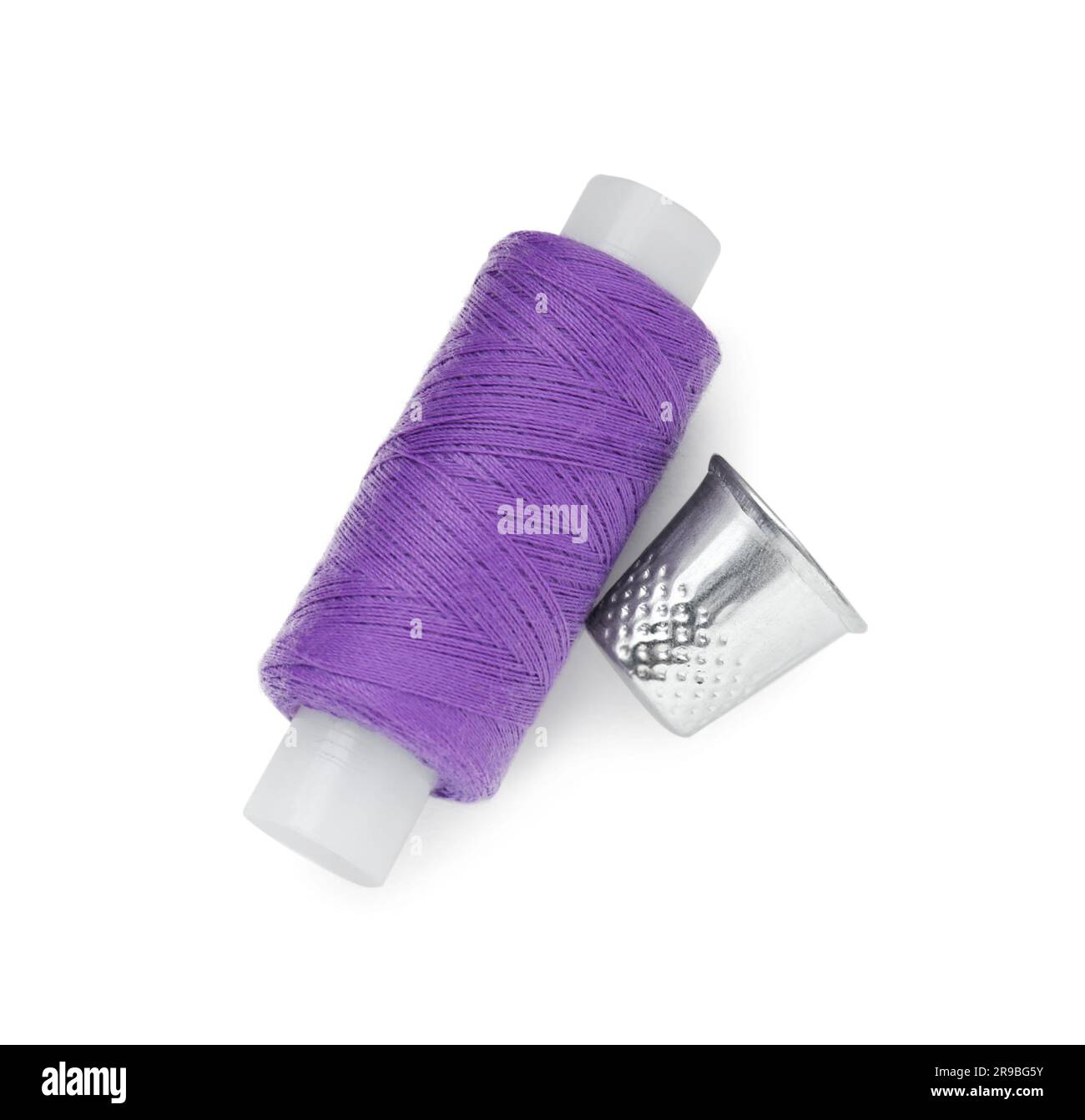 Thimble and spool of purple sewing thread isolated on white, top view ...