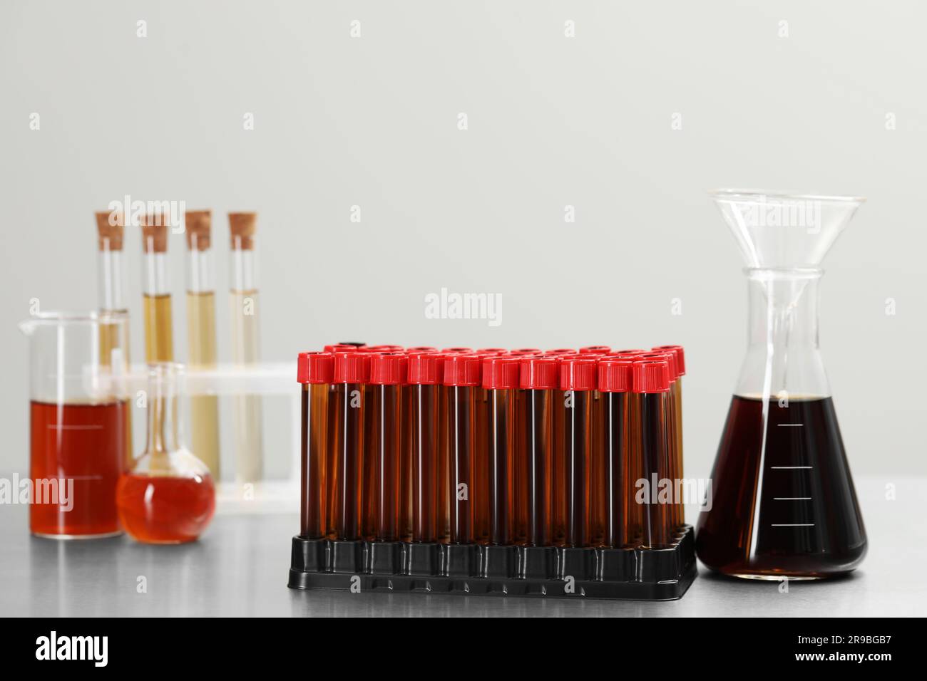 Different laboratory glassware with brown liquids on table against ...