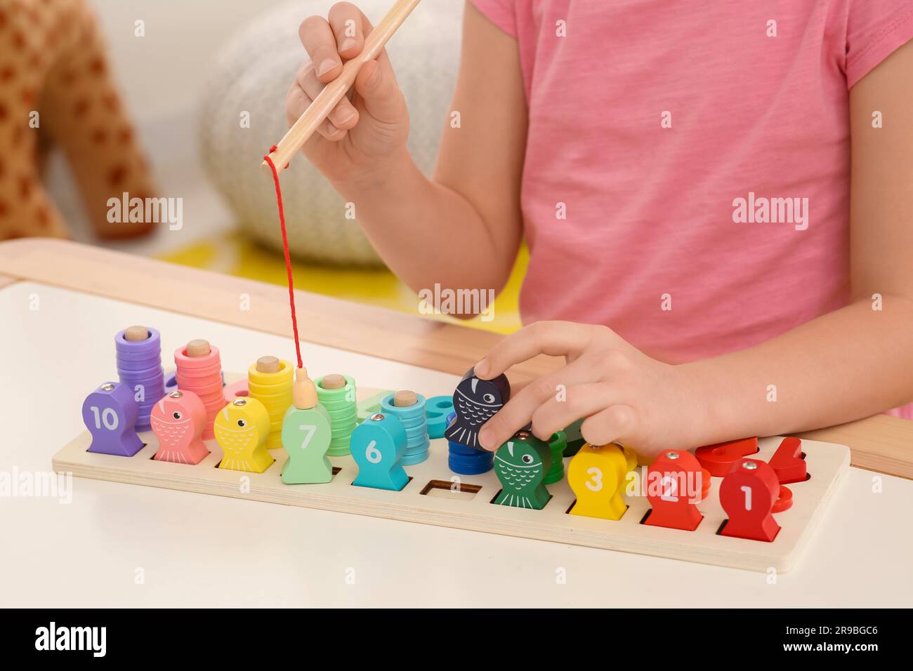 Little girl playing with Educational game Fishing for Numbers at desk ...