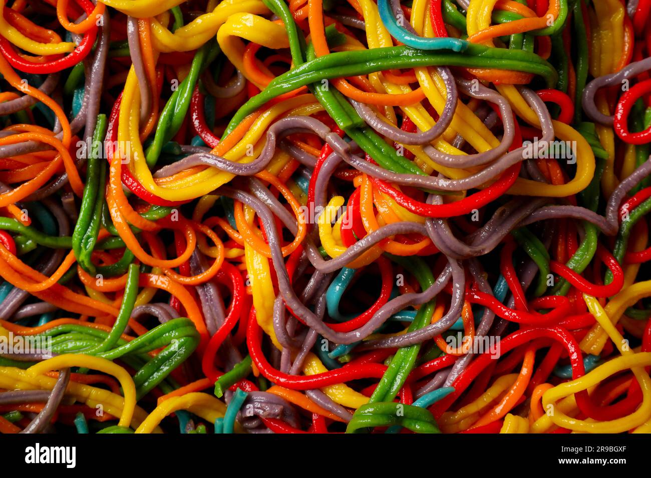 Spaghetti painted with different food colorings as background, top view ...