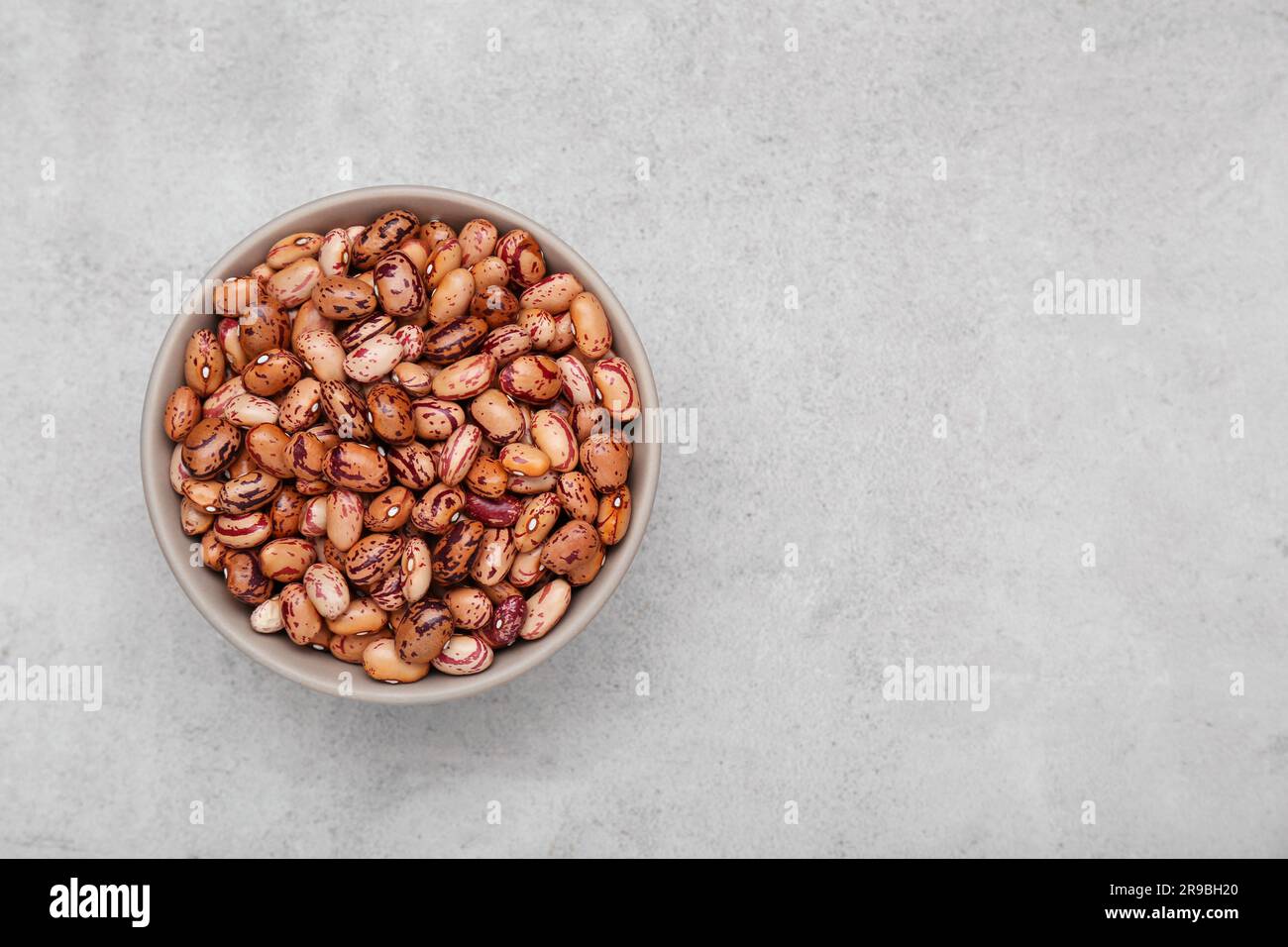 Bowl with dry kidney beans on light grey table, top view. Space for ...