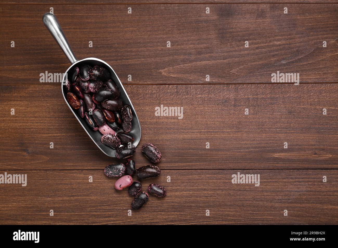 Metal scoop with dry kidney beans on wooden table, flat lay. Space for ...