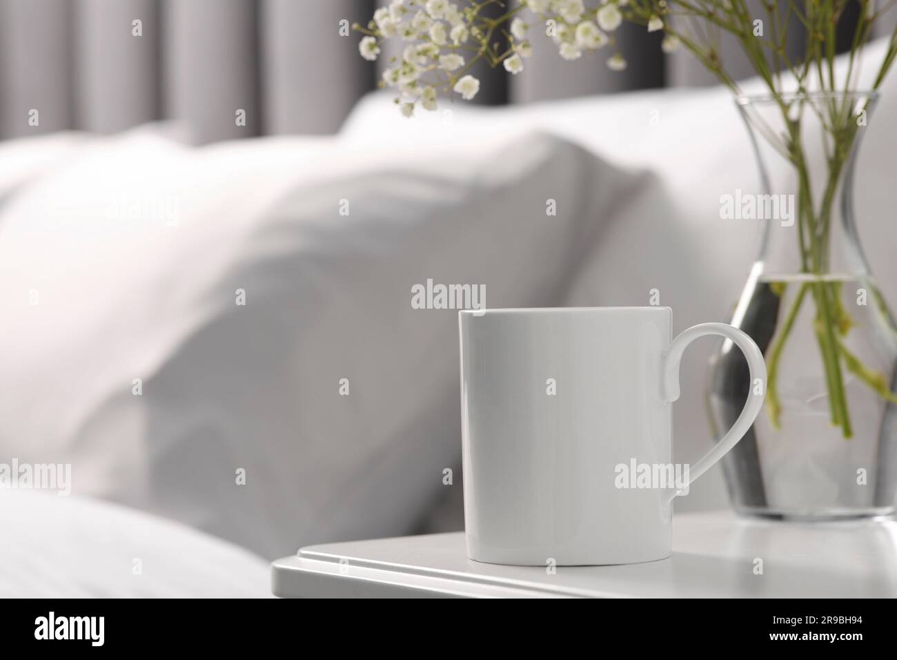 Ceramic mug on white bedside table indoors. Mockup for design Stock ...