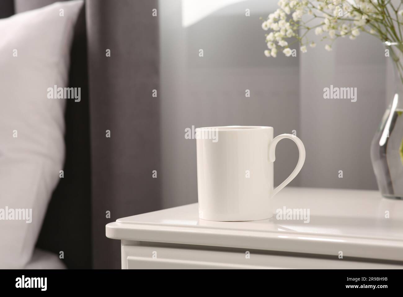 Ceramic mug on white bedside table indoors. Mockup for design Stock ...