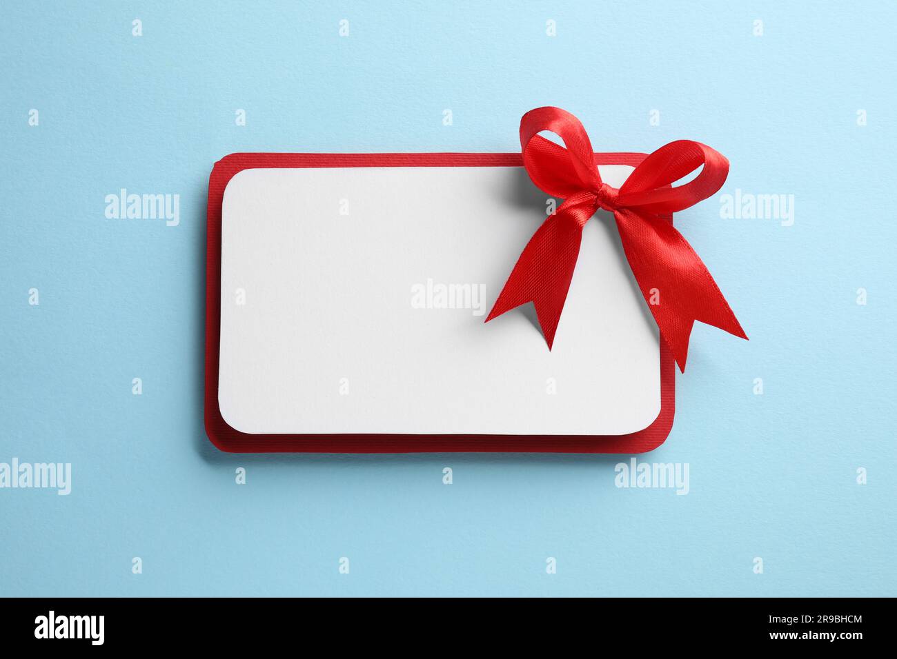 Blank gift card with red bow on light blue background, top view Stock ...