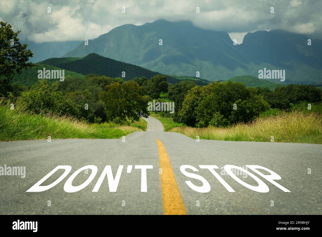Motivational phrase. Words Don't Stop written on empty road leading to ...