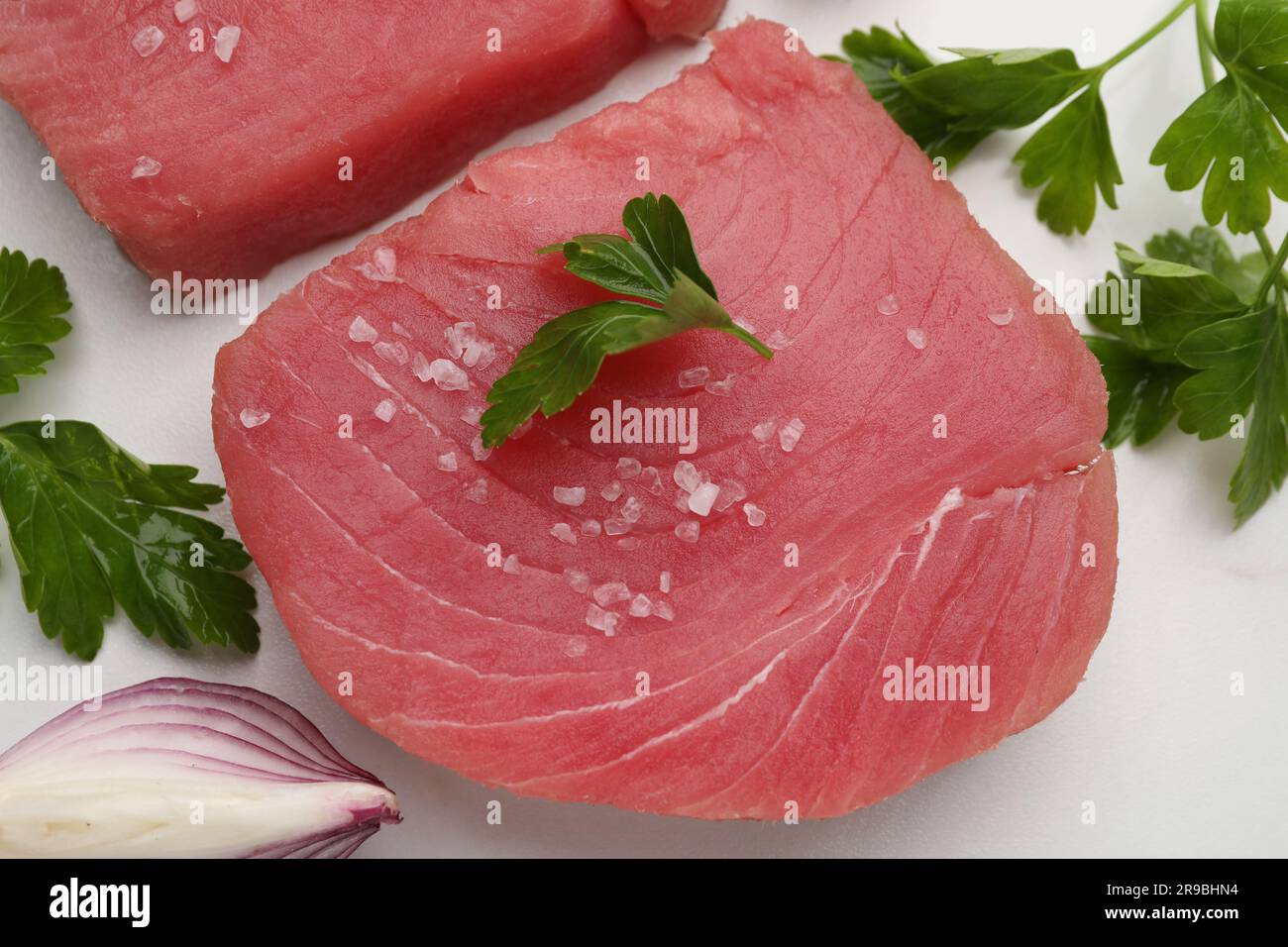 Raw tuna fillets with parsley and shallot on white table, flat lay ...