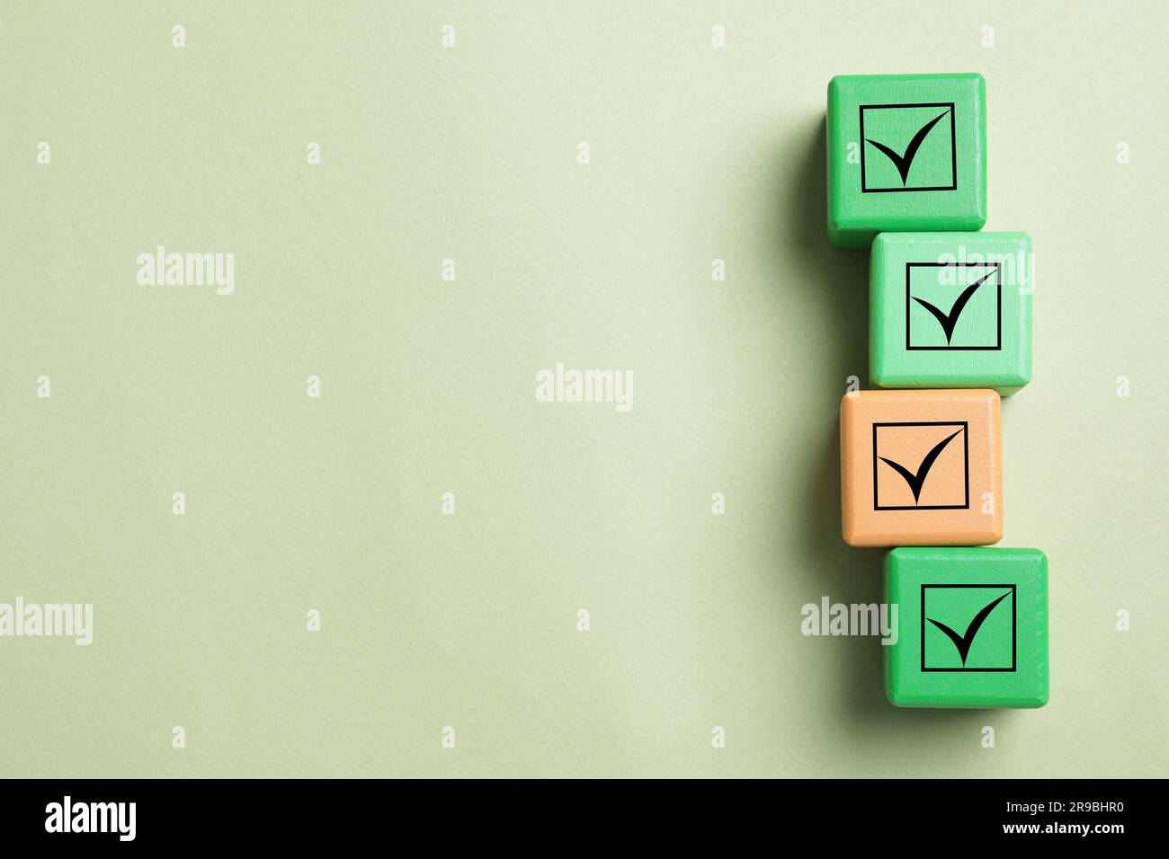 Cubes with check marks on light olive color background, flat lay. Space ...