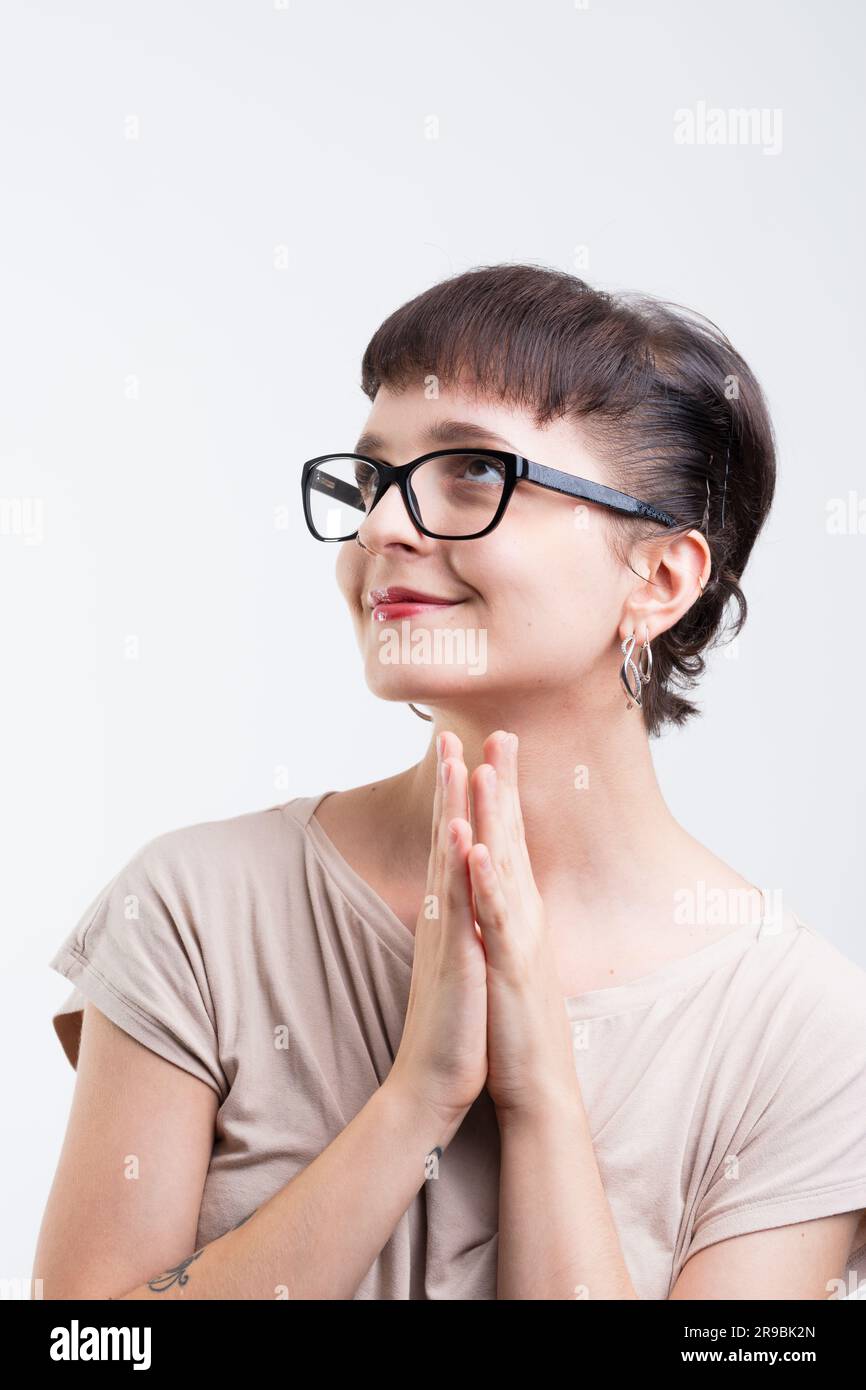 Woman with many hairpins, glasses, joined hands, sly smile, feigns ...