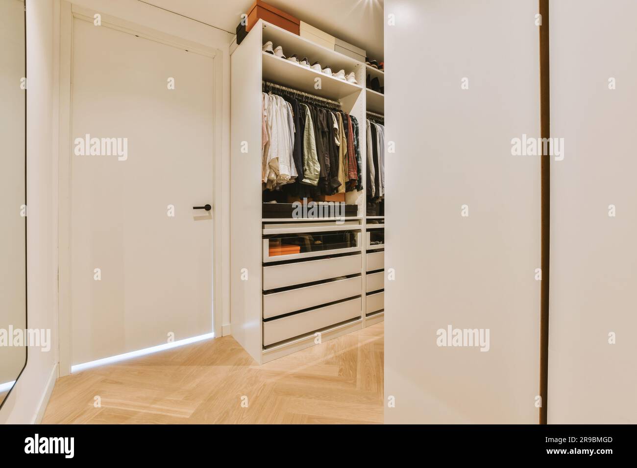 a walk - in closet with clothes hanging on the wall and an open door ...