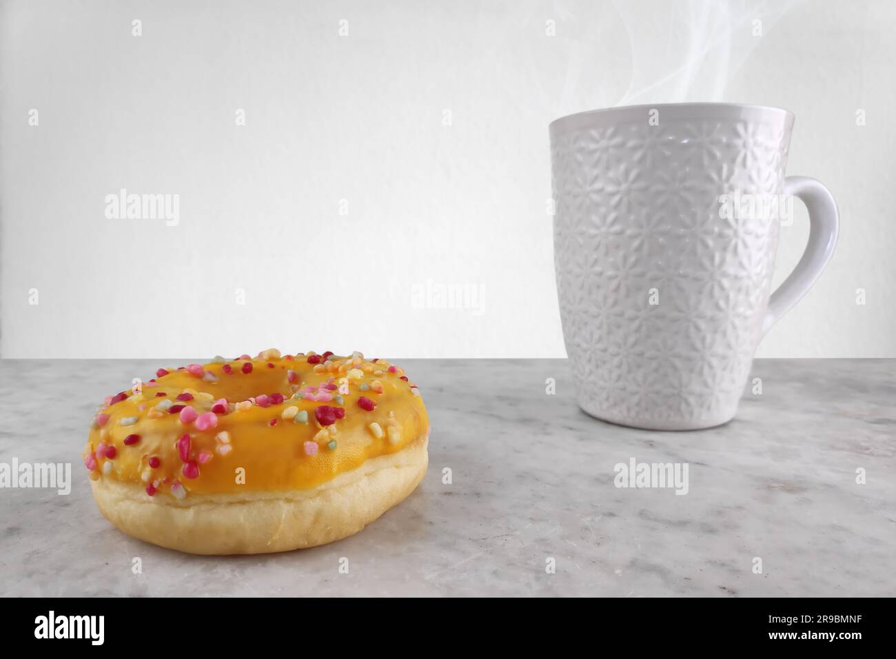 A donut with yellow icing topped with small colorful sugar crumb next ...