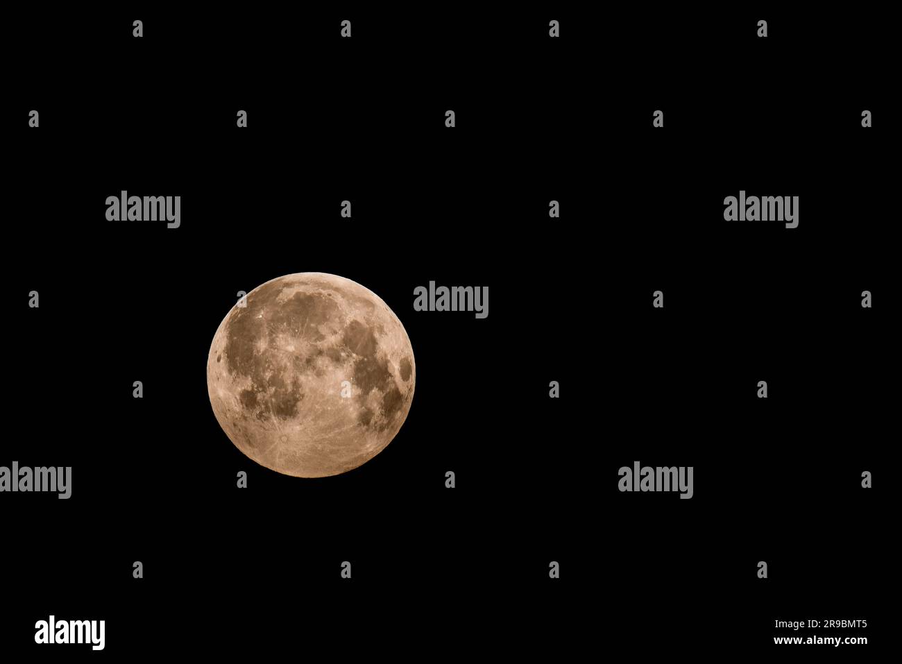 A large, full moon with a vivid light brown hue in the night sky Stock ...