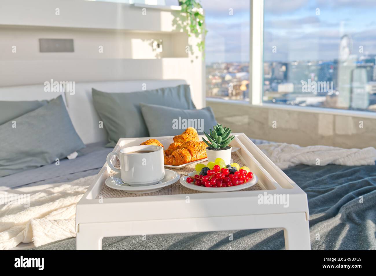 White Tray with tasty breakfast on bed in light bedroom with big ...