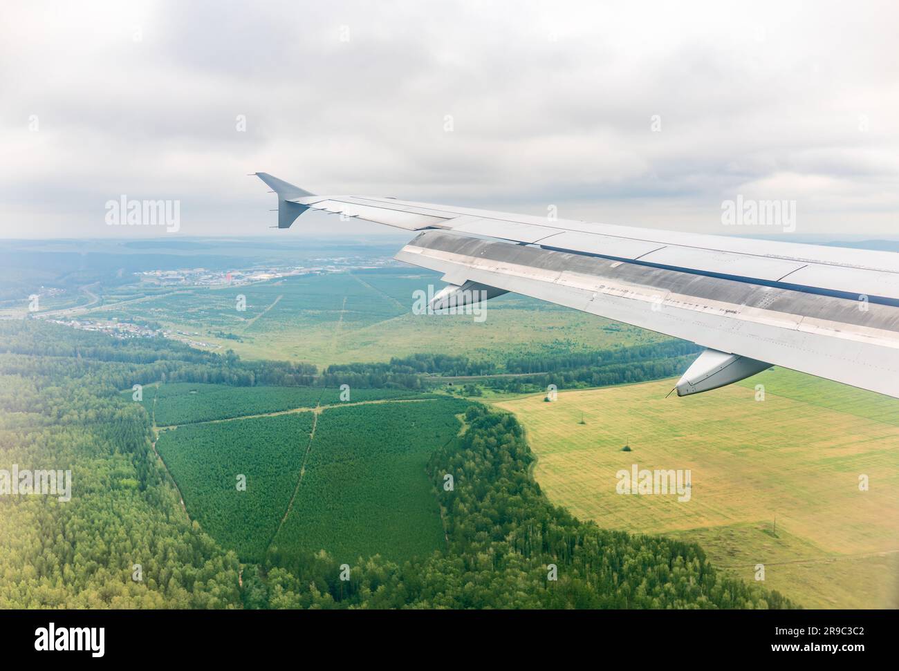 View of airplane wing, blue skies and green land during landing ...