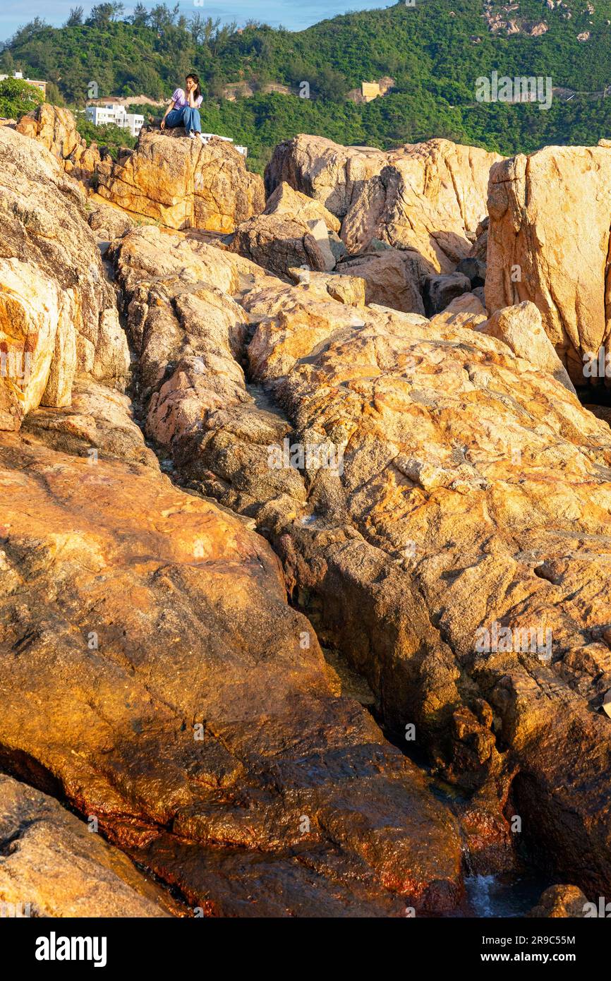 Chinese girl posing for photograph on rocks, Stanley Harbour, Hong Kong ...
