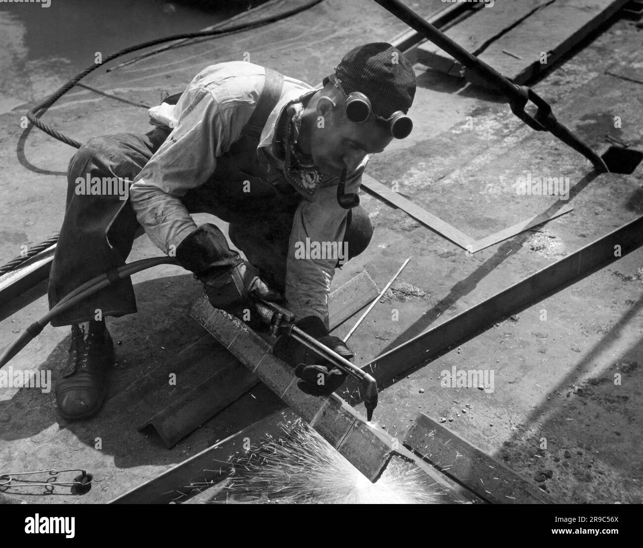 United States: c. 1938 A workman using an oxy acetylene torch to cut ...
