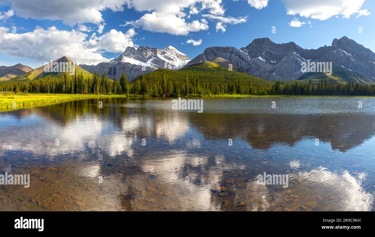 Clouds and Distant Rocky Mountain Peaks Reflected in Calm Blue Lake ...