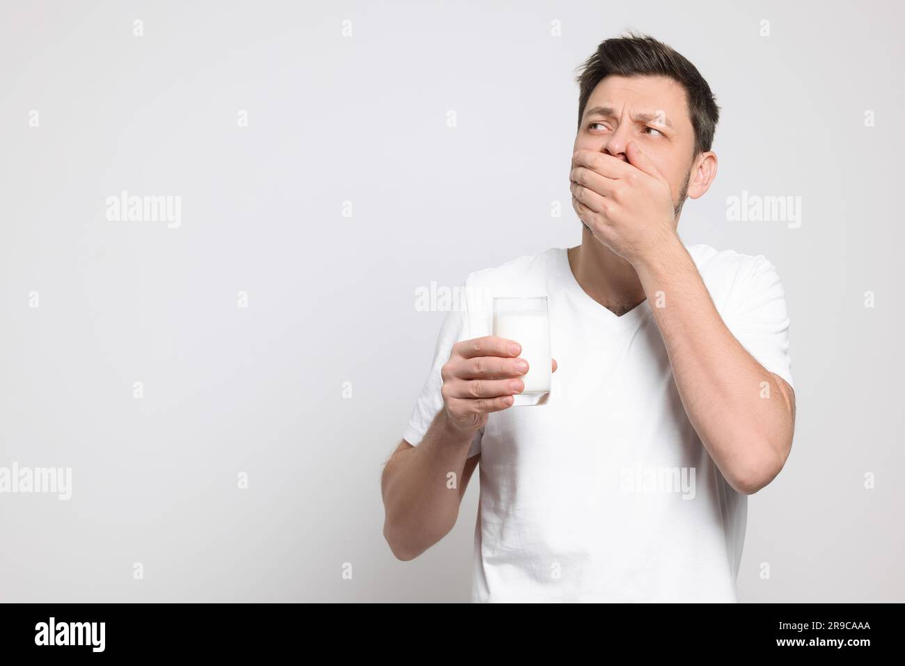Man with glass of milk suffering from lactose intolerance on white ...