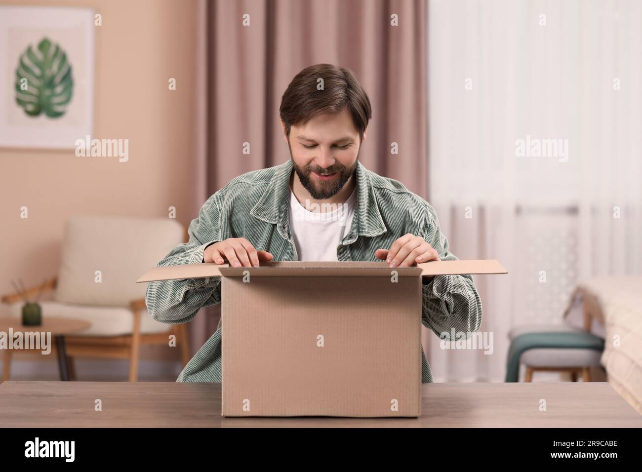 Happy man opening parcel at home. Internet shopping Stock Photo - Alamy