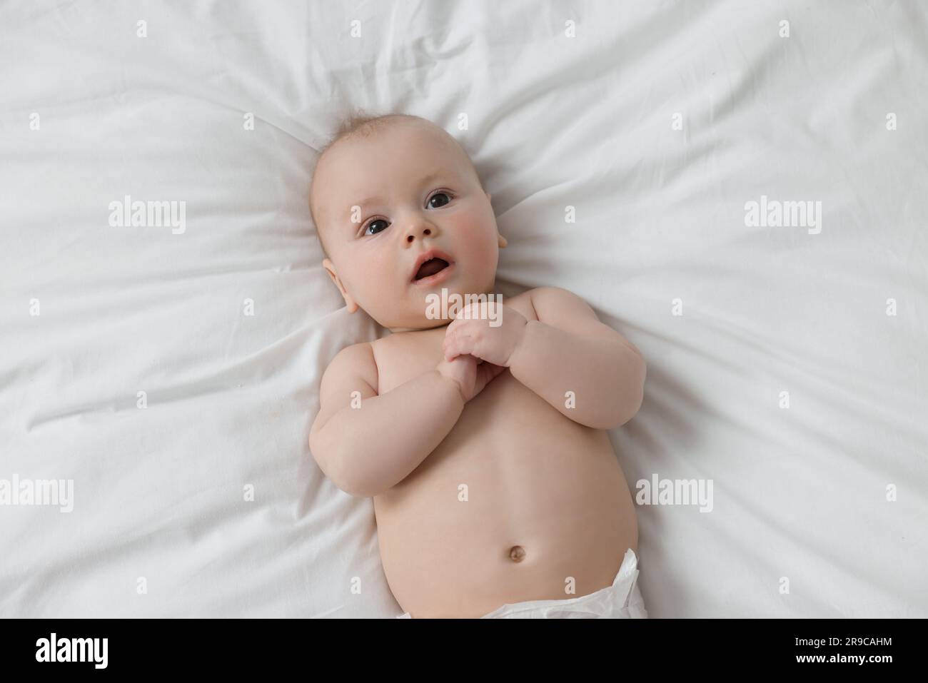Cute little baby lying on white bed, top view Stock Photo - Alamy