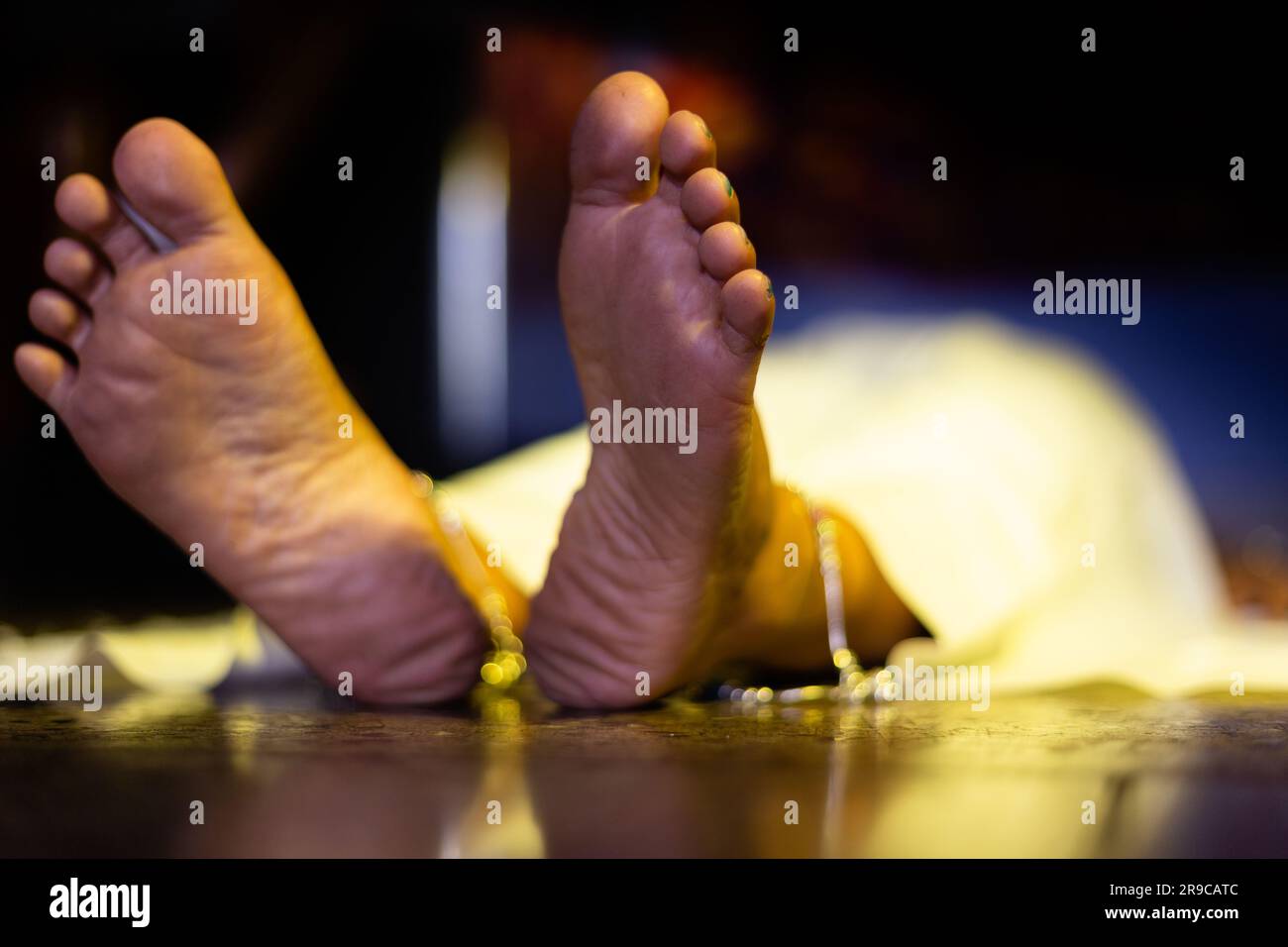 Feet of an Indian or Asian female dead body lying on floor in a dark ...