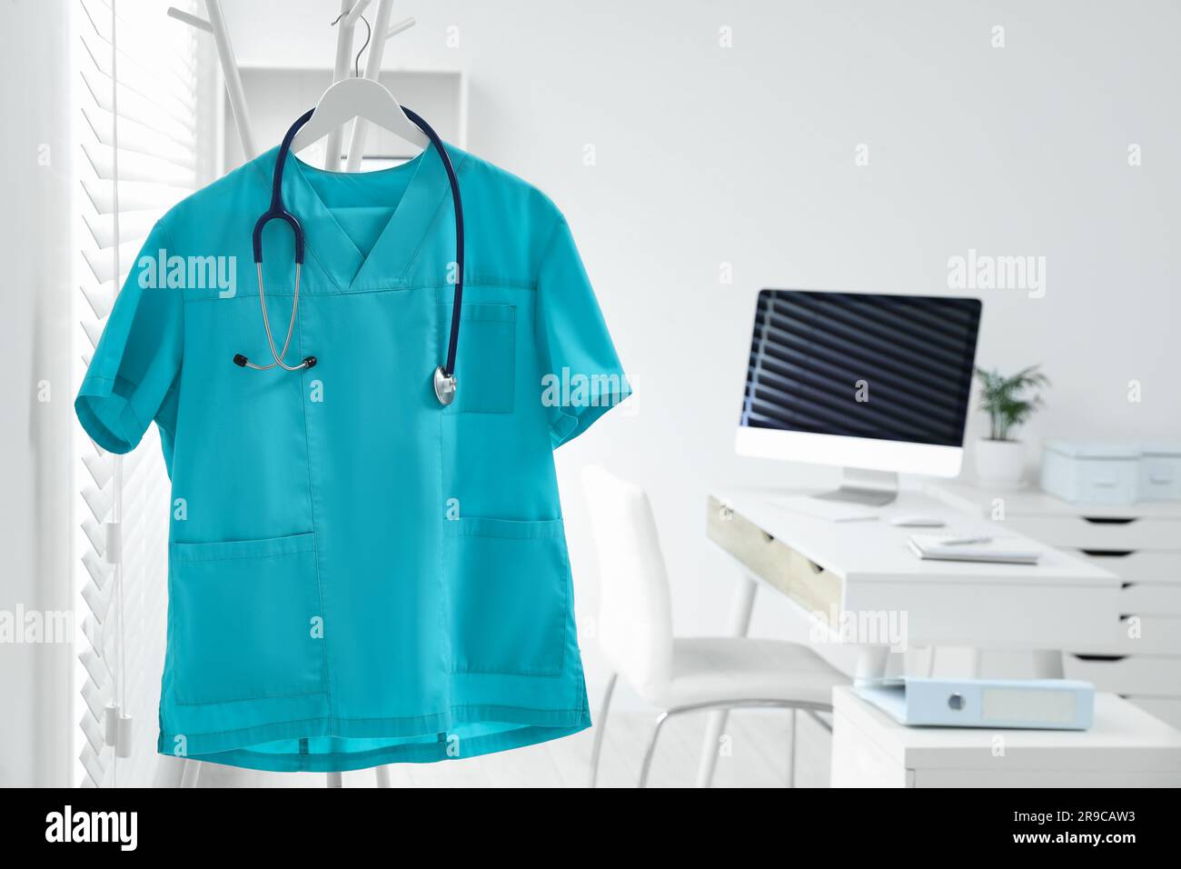 Turquoise medical uniform and stethoscope hanging on rack in clinic ...