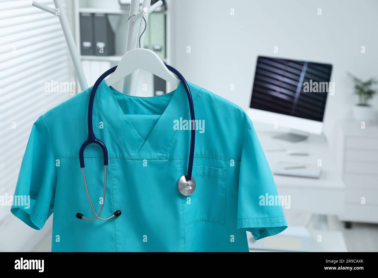 Turquoise medical uniform and stethoscope hanging on rack in clinic ...