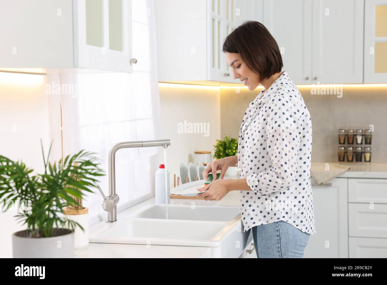 Happy young woman washing plate above sink in modern kitchen Stock ...