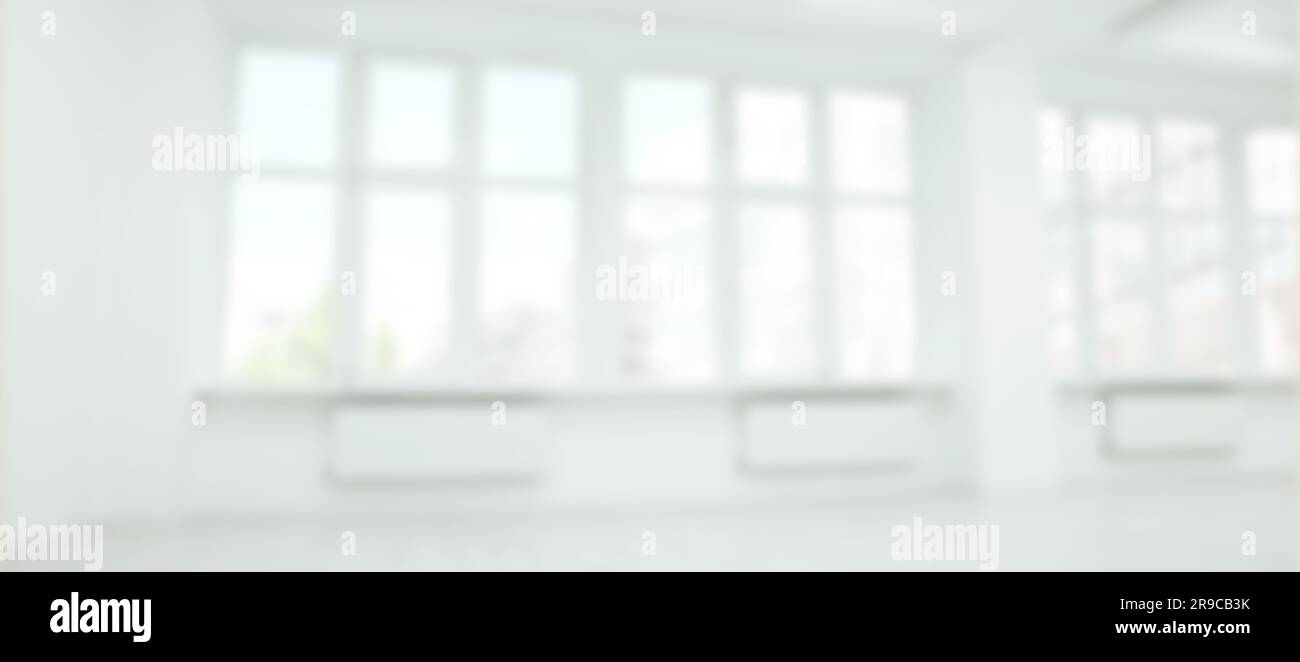 Empty room with white wall and large windows, blurred view. Banner ...