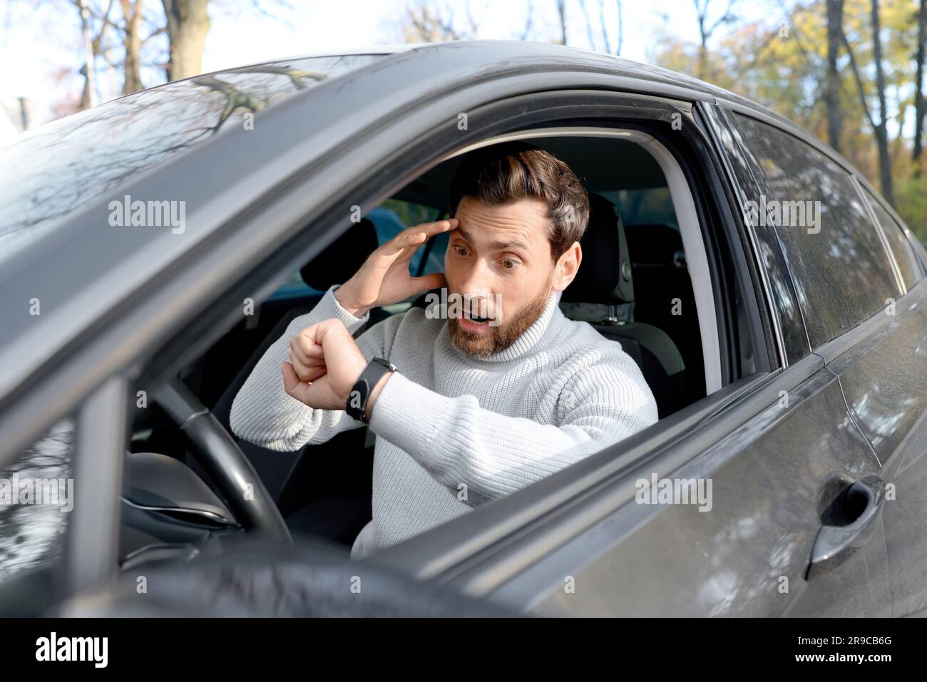 Emotional man checking time on watch in car. Being late concept Stock ...