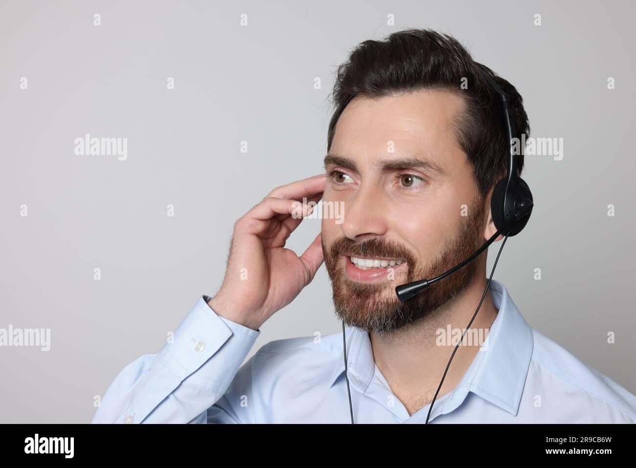 Hotline operator with headset on light grey background, space for text ...