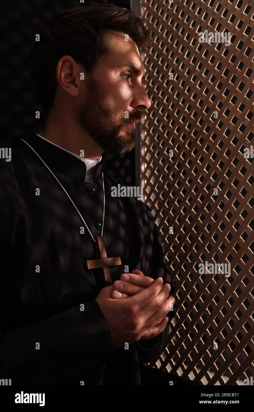 Catholic priest wearing cassock in confessional booth Stock Photo - Alamy