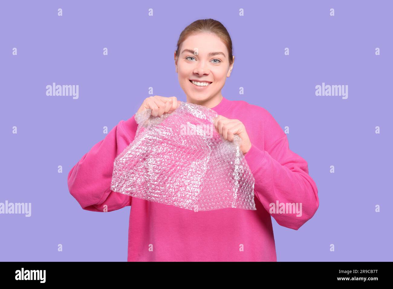 Woman popping bubble wrap on purple background. Stress relief Stock ...